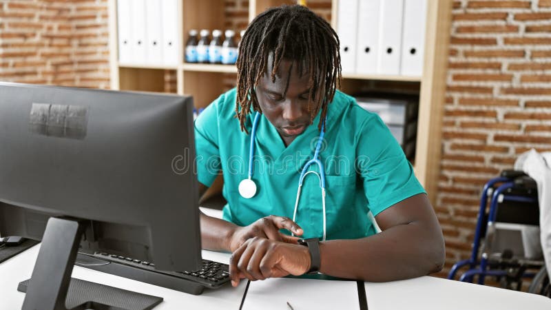 African American Man Doctor Using Computer Looking Watch with Serious ...