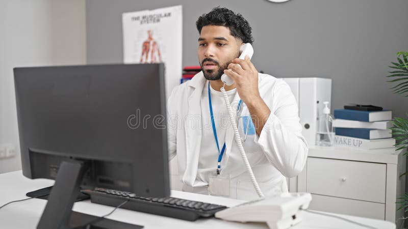 African American Man Doctor Using Computer Talking on Telephone at ... African American Man Doctor Using Computer Talking on Telephone at ...