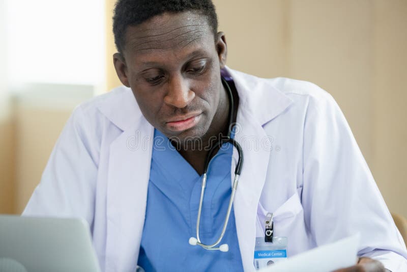 African American Man Doctor Using Laptop and Paperwork Checking Report ...