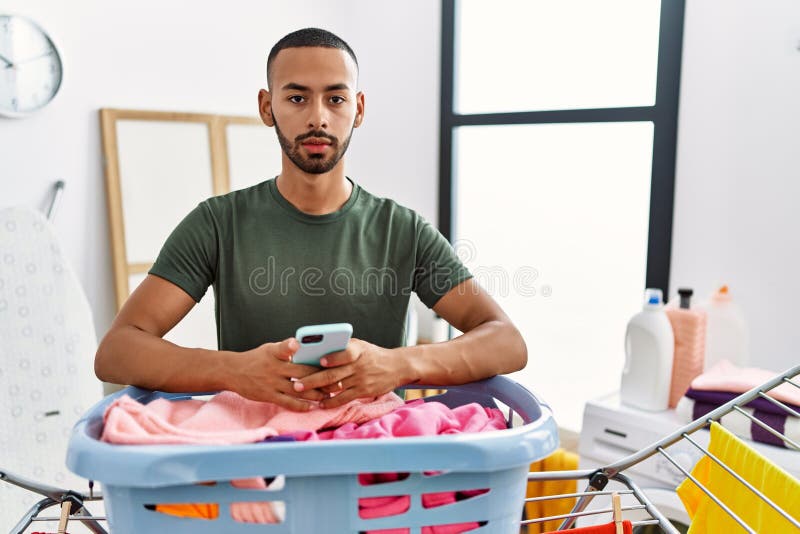 African American Man Doing Laundry Using Smartphone Relaxed with ...