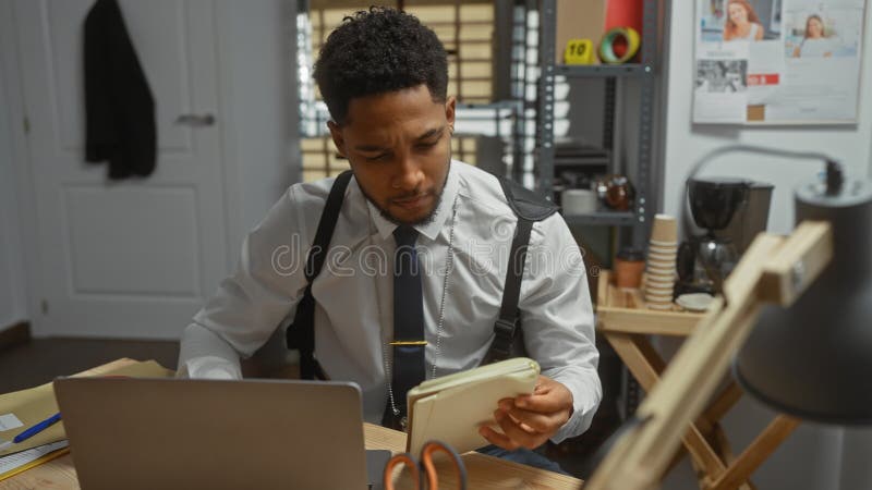 African American Man Examines Documents at a Police Station, Typifying ...