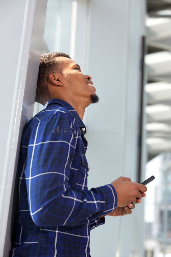 African American Man Leaning Against Wall Using Cell Phone Stock Image ...