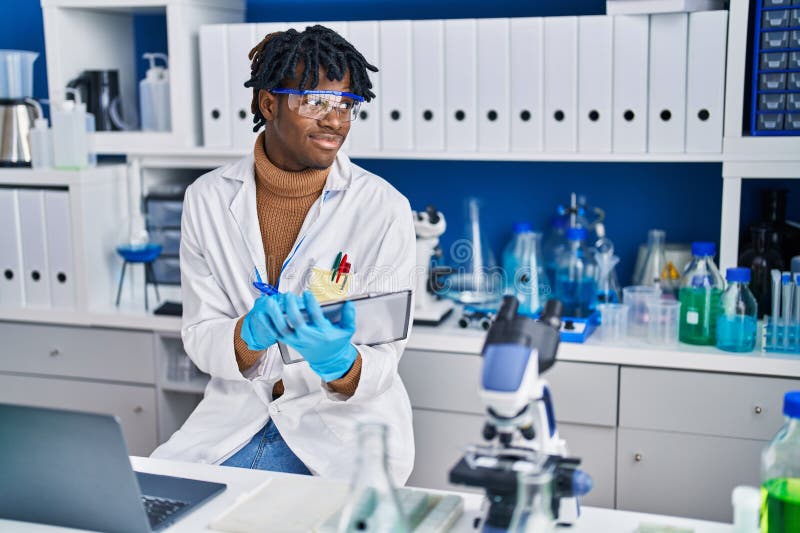 African American Man Scientist Using Laptop Writing on Clipboard at ...