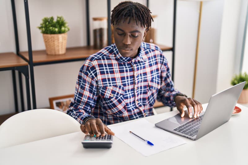 African American Man Using Laptop and Calculator Accounting at Home ...