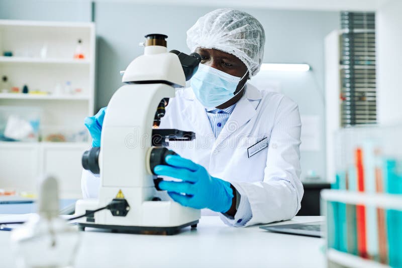 African American Man Using Microscope Doing Research in Laboratory ...
