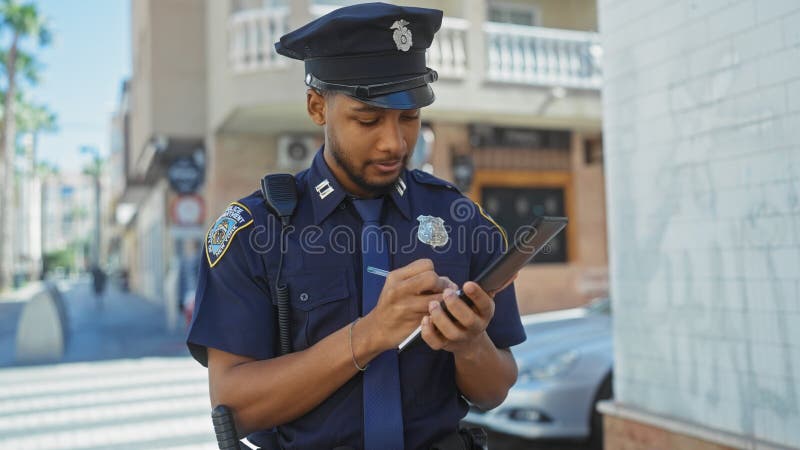 African American Policeman Taking Notes on Tablet on City Street Stock ...