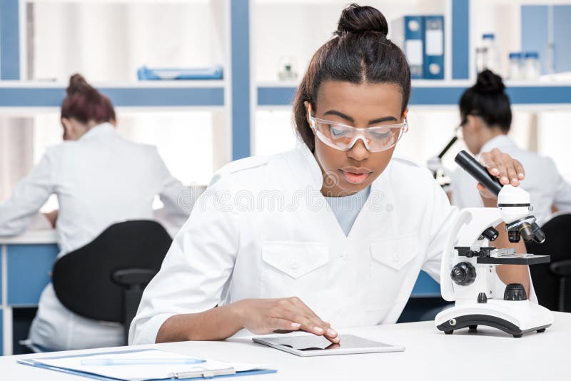 African American Scientist in Lab Coat with Microscope and Digital ...