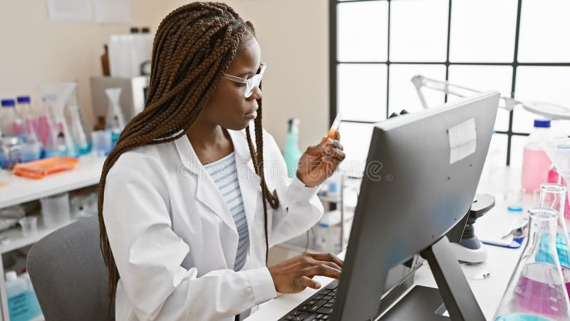 African American Scientist Woman Examining a Sample while Working with ...