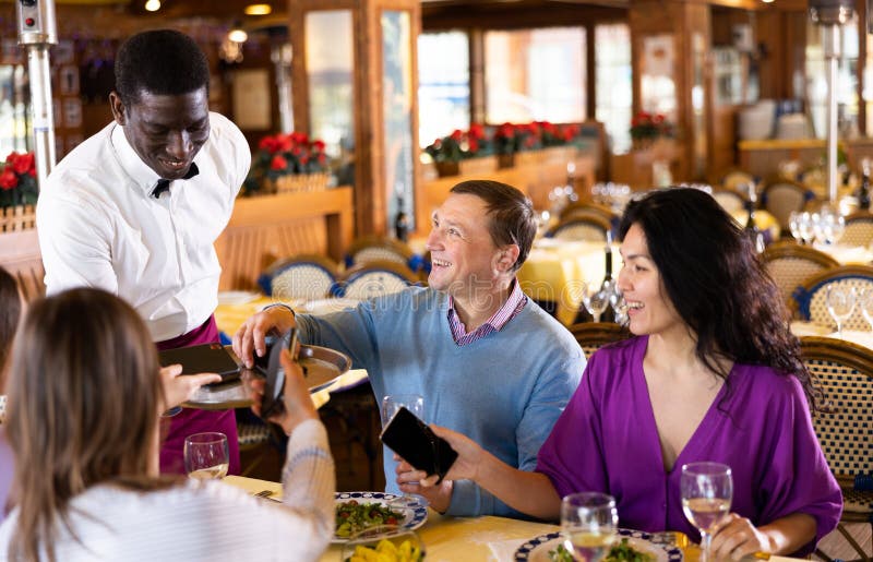 African American Waiter Brought Mobile Phones On The Tray Of Restaurant