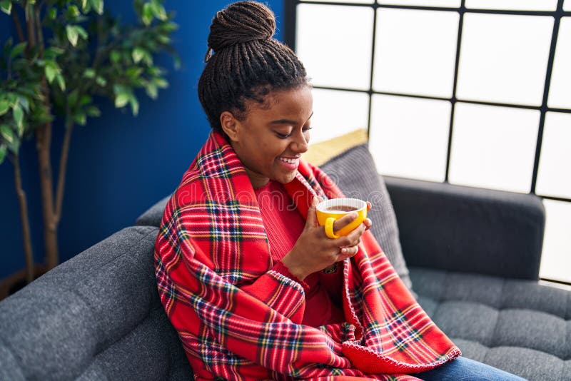 African American Woman Drinking Coffee Sitting On Sofa At Home Stock