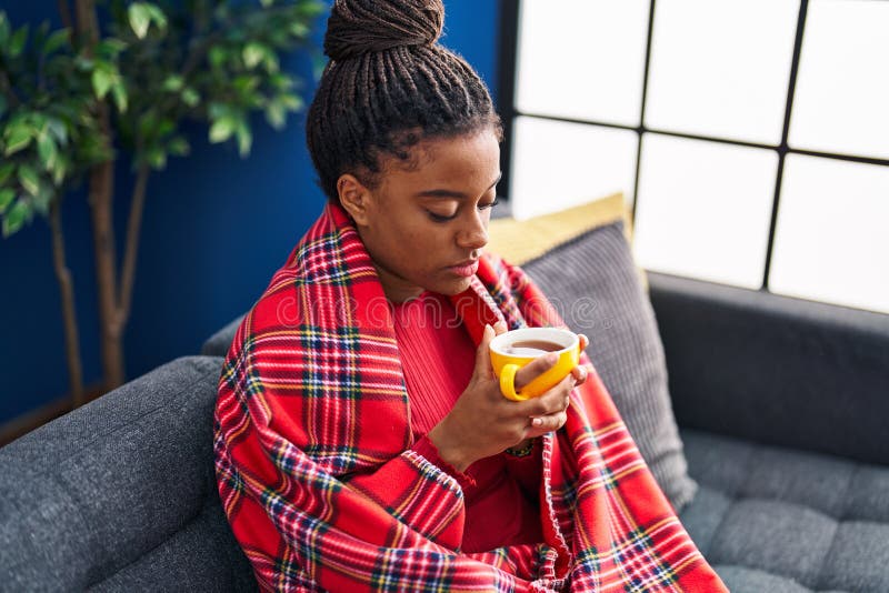 African American Woman Drinking Coffee Sitting On Sofa At Home Stock