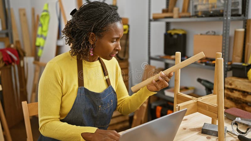 African American Woman Examines Wood in a Carpentry Workshop Surrounded ...