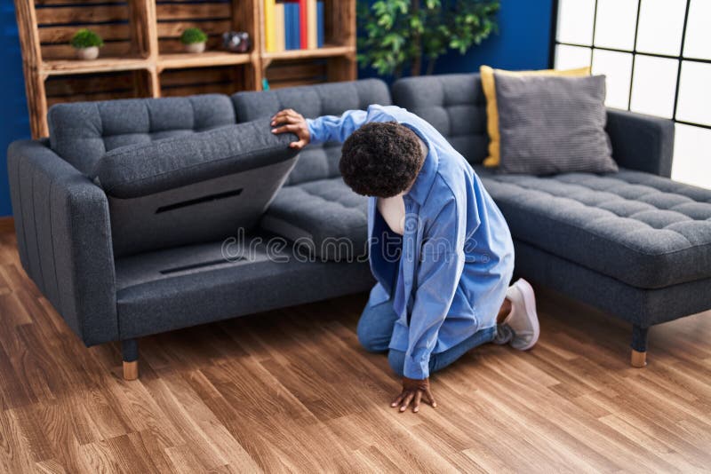 African American Woman Looking for Under Sofa at Home Stock Photo ...