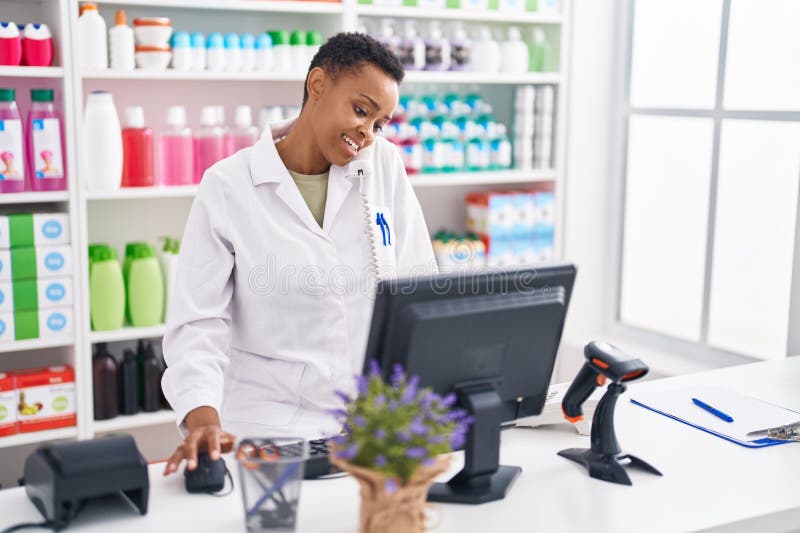 African American Woman Pharmacist Talking on Telephone Using Computer ...