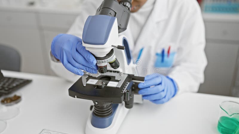African American Woman Scientist Examining Samples Under a Microscope ...
