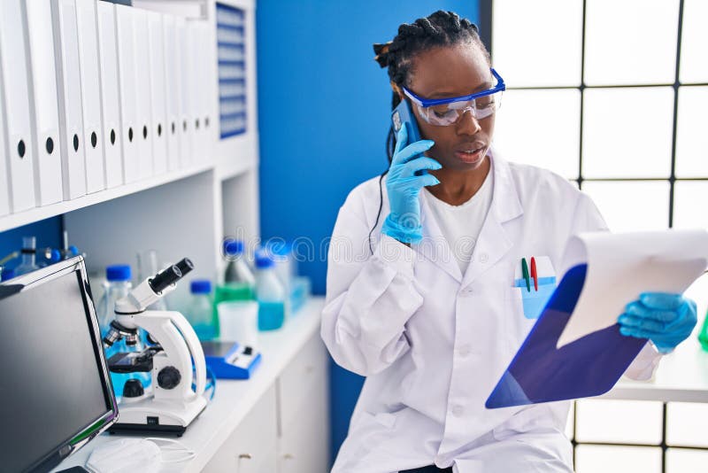 African American Woman Scientist Reading Document at Laboratory Stock ...