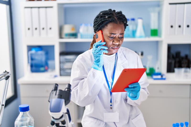 African American Woman Scientist Talking on Smartphone Using Touchpad ...