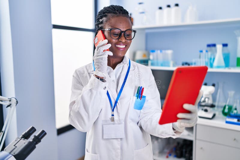 African American Woman Scientist Talking on Smartphone Using Touchpad ...