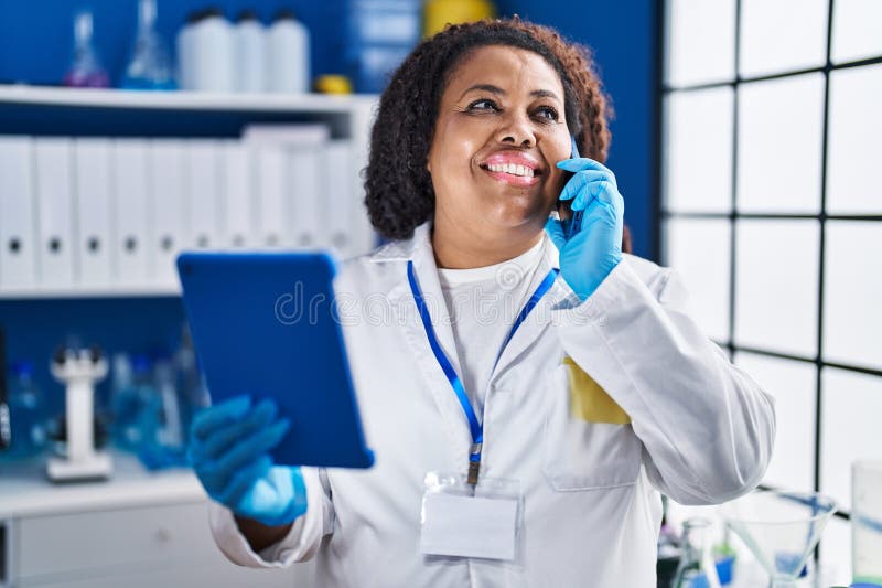 African American Woman Scientist Talking on Smartphone Using Touchpad ...
