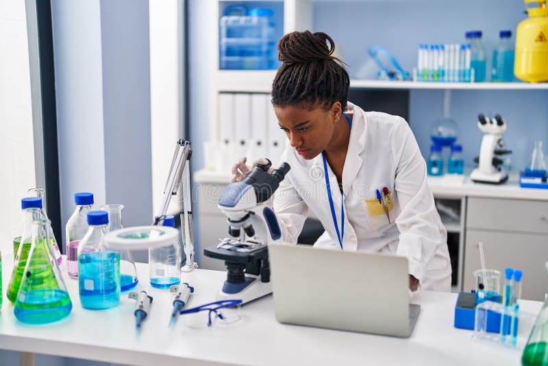 African American Woman Scientist Using Laptop and Microscope at ...