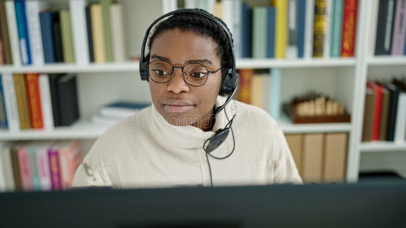 African American Woman Student Using Computer and Headphones at Library ...