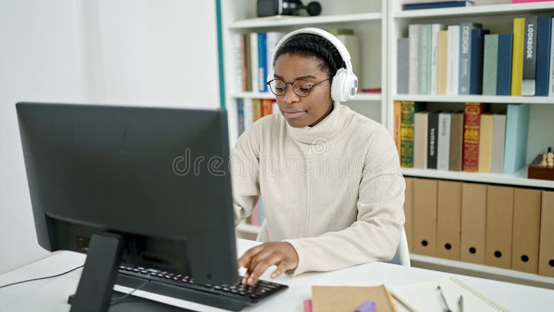 African American Woman Student Using Computer and Headphones Studying ...