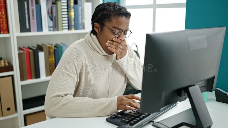 African American Woman Student Using Computer Yawning at Library ...