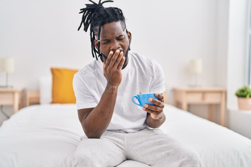 African American Woman Tired Drinking Coffee Sitting On Bed At Bedroom