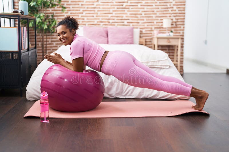 African American Woman Training Core Exercise Using Fit Ball at Bedroom ...