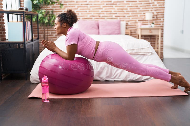African American Woman Training Core Exercise Using Fit Ball at Bedroom ...