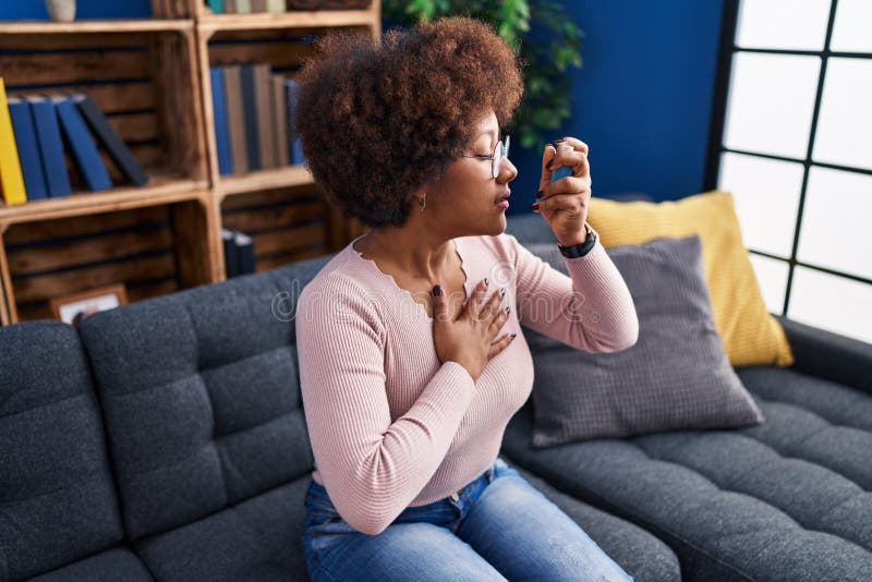 African American Woman Using Inhaler Sitting on Sofa at Home Stock ...