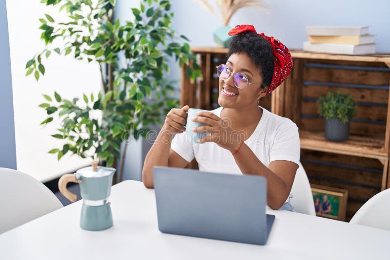 African American Woman Using Laptop And Drinking Coffee Sitting On