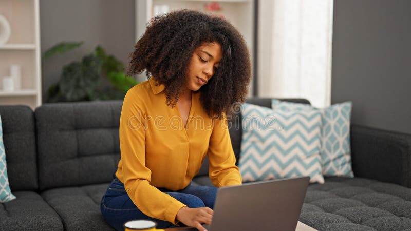 African American Woman Using Laptop Sitting on Sofa at Home Stock Photo ...