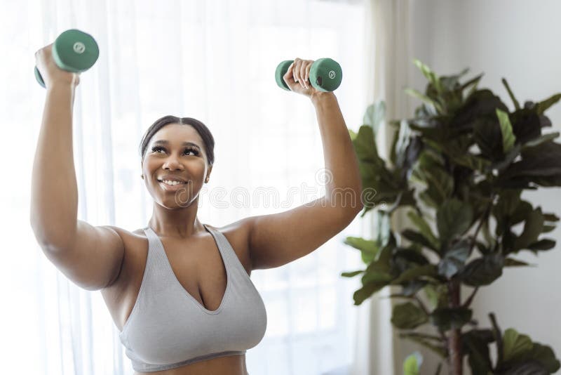 African American Woman Working Out In Home Livingroom Gym Lift Dumbbell