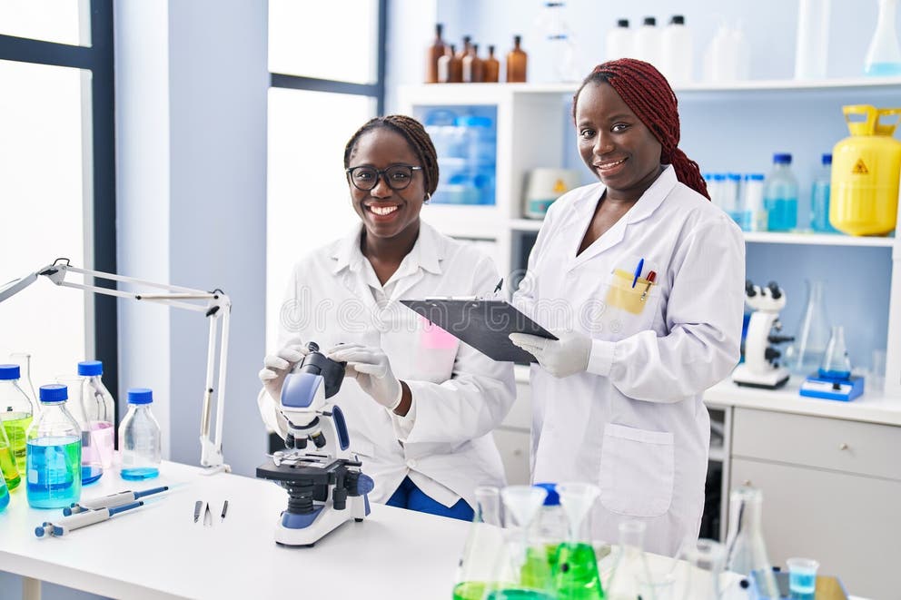 African American Women Scientists Using Microscope Writing on Document ...