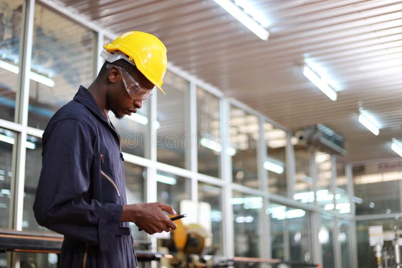 African American Worker in Safety Suit and Hardhat Using Mobile Phone ...