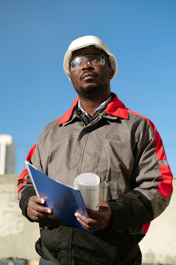 African American Worker Stands at Construction Site with Work Papers ...