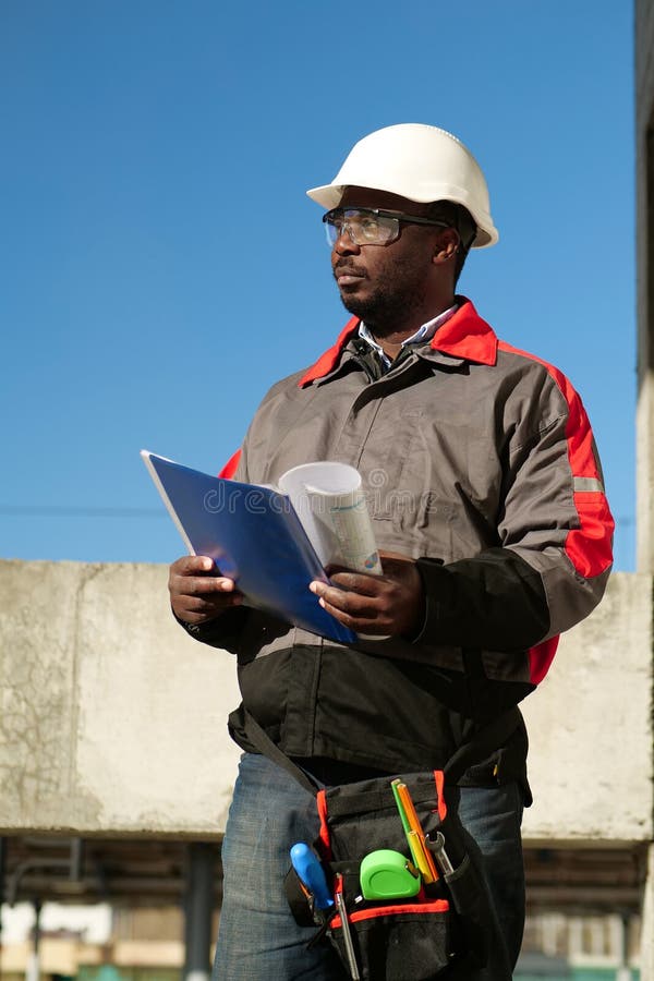 African American Worker Stands at Construction Site with Work Papers ...