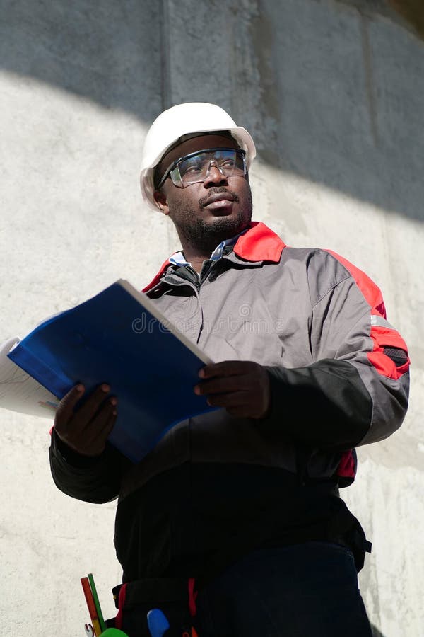 African American Worker Stands at Construction Site with Work Papers ...