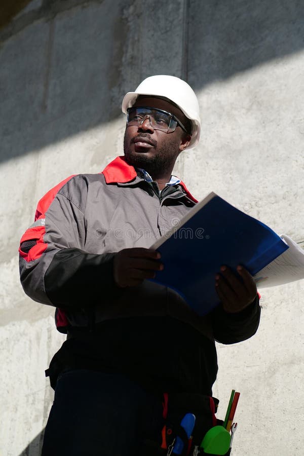 African American Worker Stands at Construction Site with Work Papers ...