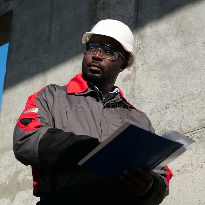 African American Worker Stands at Construction Site with Work Papers ...