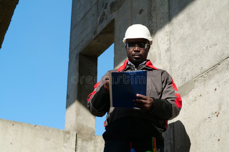African American Worker Stands at Construction Site with Work Papers ...