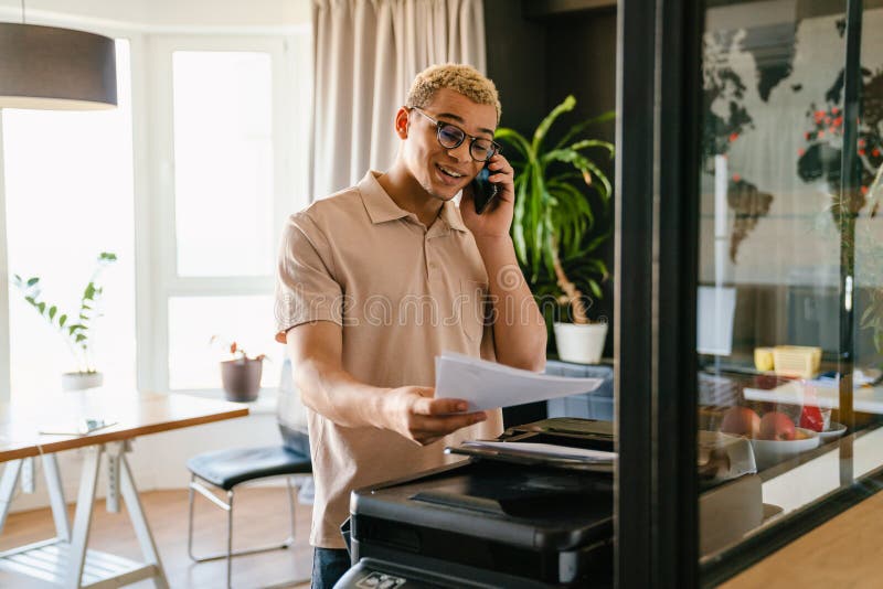 African Business Man Using Printer while Talking on Mobile Phone in ...
