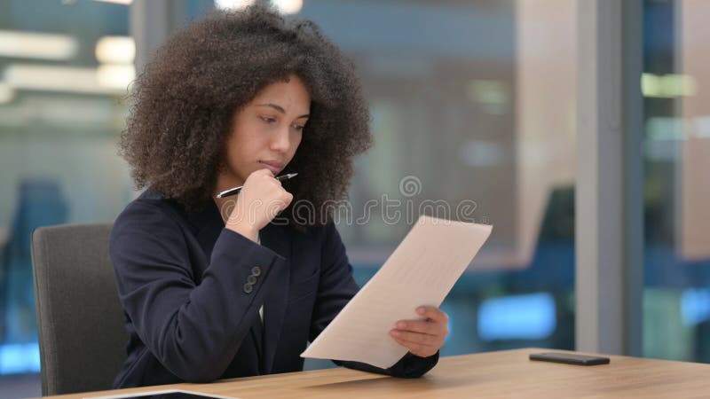 African Businesswoman Reading Documents at Work Stock Image - Image of ...