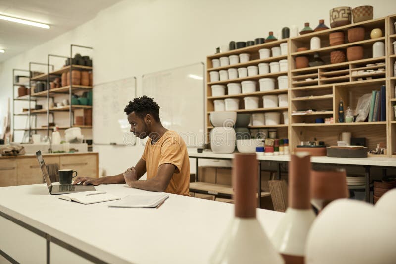 African Ceramics Workshop Manager Using on a Laptop at a Table Stock Photo - Image of bench ...