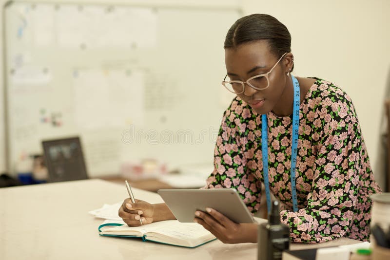 African Female Clothes Designer Working on a Tablet in Her Studio Stock ...