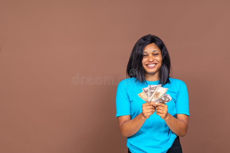 African Female Holding Money Posing in Front of a Brown Wall Stock ...