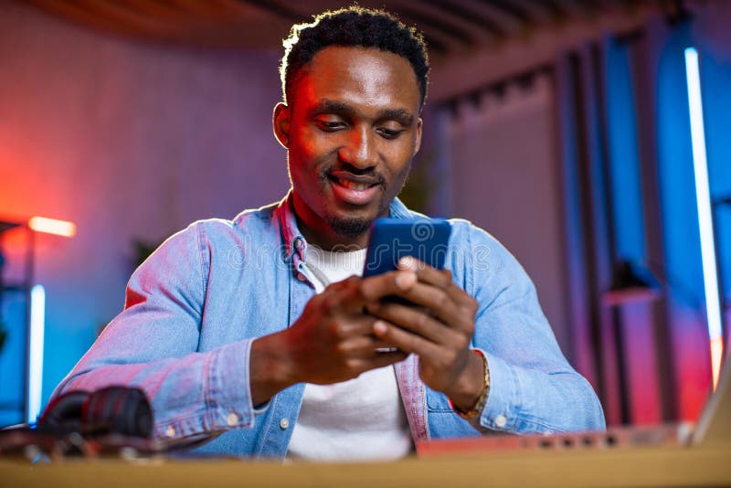 African Guy Sitting at Table Laptop and Holding Smartphone Stock Photo ...