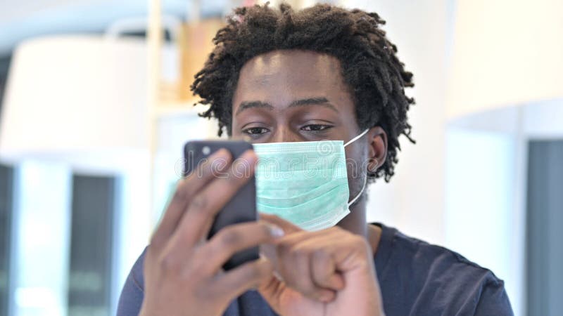 African Man with Face Mask Using Smartphone Stock Photo - Image of ...
