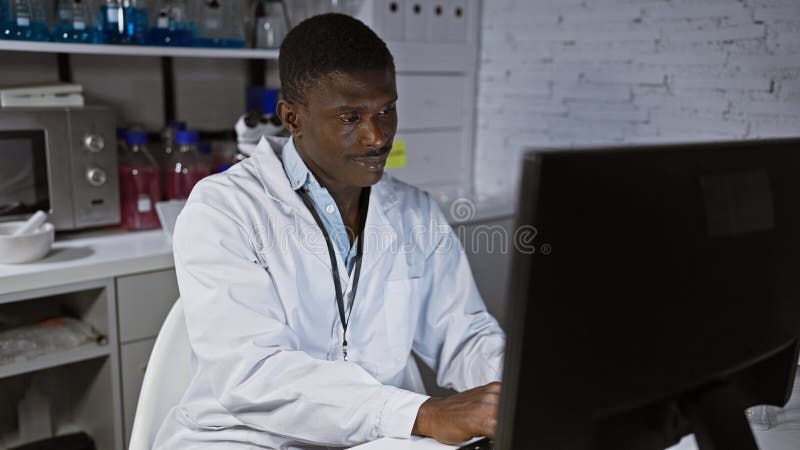 African Man in Lab Coat Working on Computer in a Modern Laboratory ...
